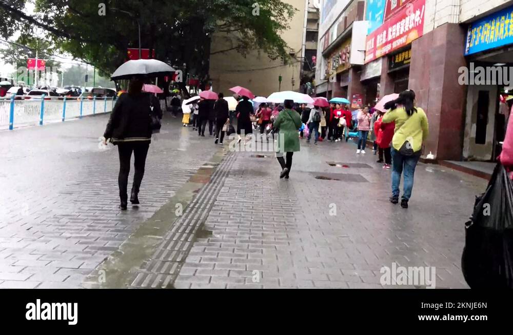 CHINA CHONGQING crowd of people walking in the rain near Xiaoshizi ...