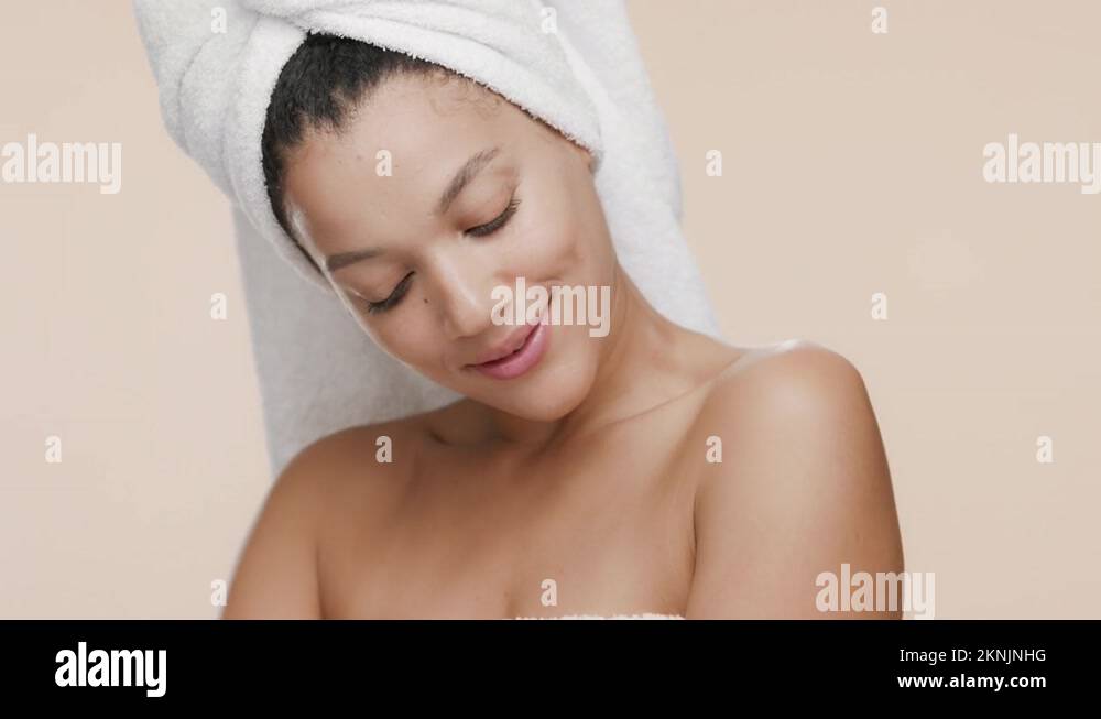 African slim woman with a towel on hair stokes shoulder smiling Stock ...