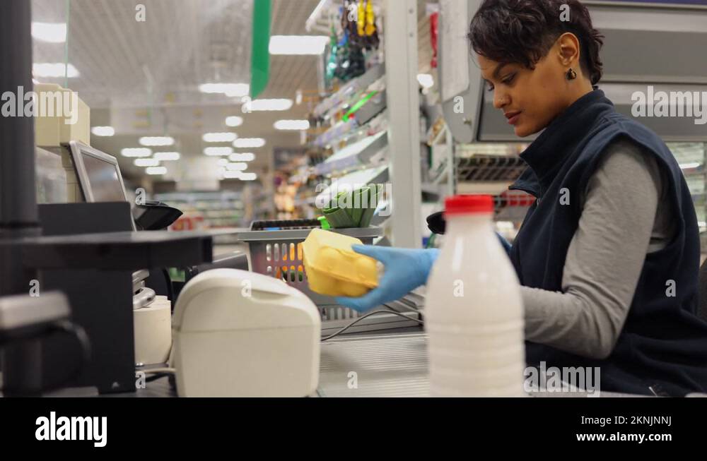Young woman cashier scanning fresh food and working at checkout of ...