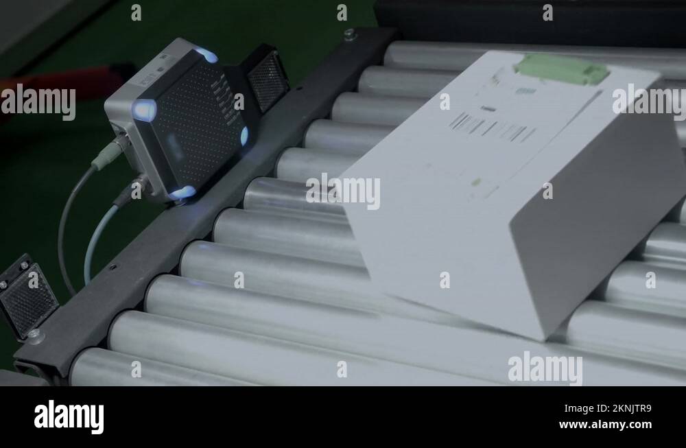 An industrial laser sensor on a conveyor detects the passage of a white ...