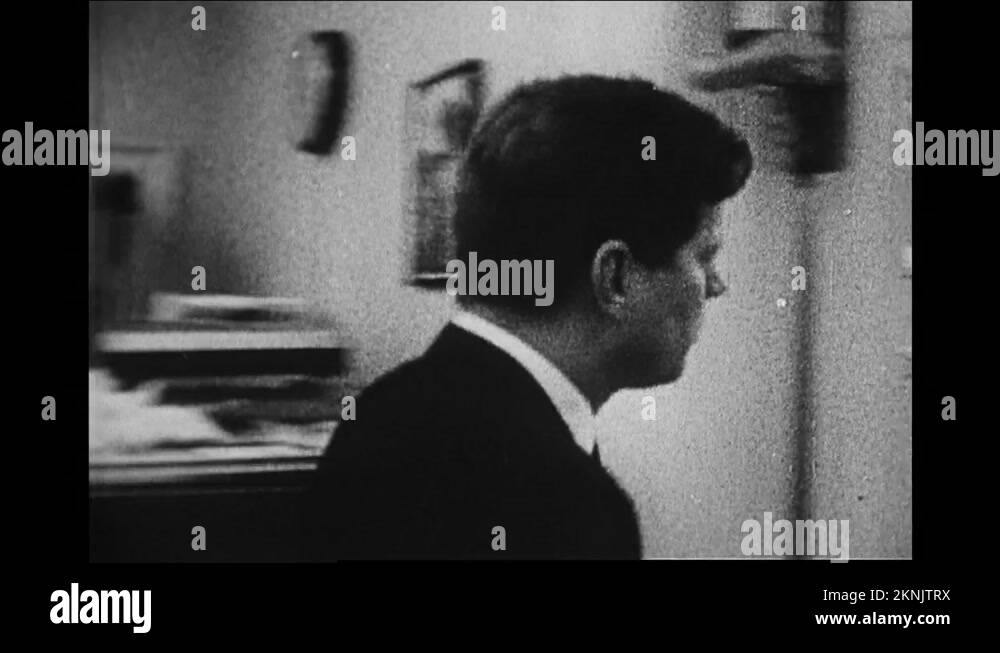 1960s: Photo of John F Kennedy, zoom out to men. Kennedy enters room ...