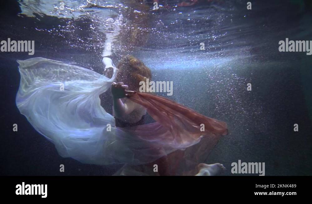 mystery and magic underwater, graceful woman is swimming slowly ...