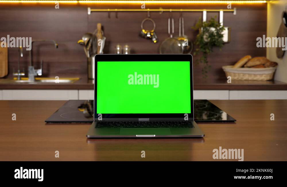 Green screen laptop standing on kitchen table, computer with chroma key ...