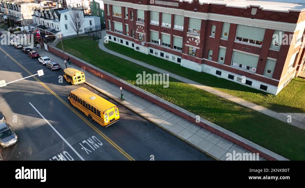 School bus and students at public school building. Exterior aerial ...
