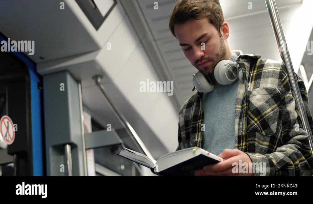 Handheld, young guy rides the subway and reads a book, a student goes ...