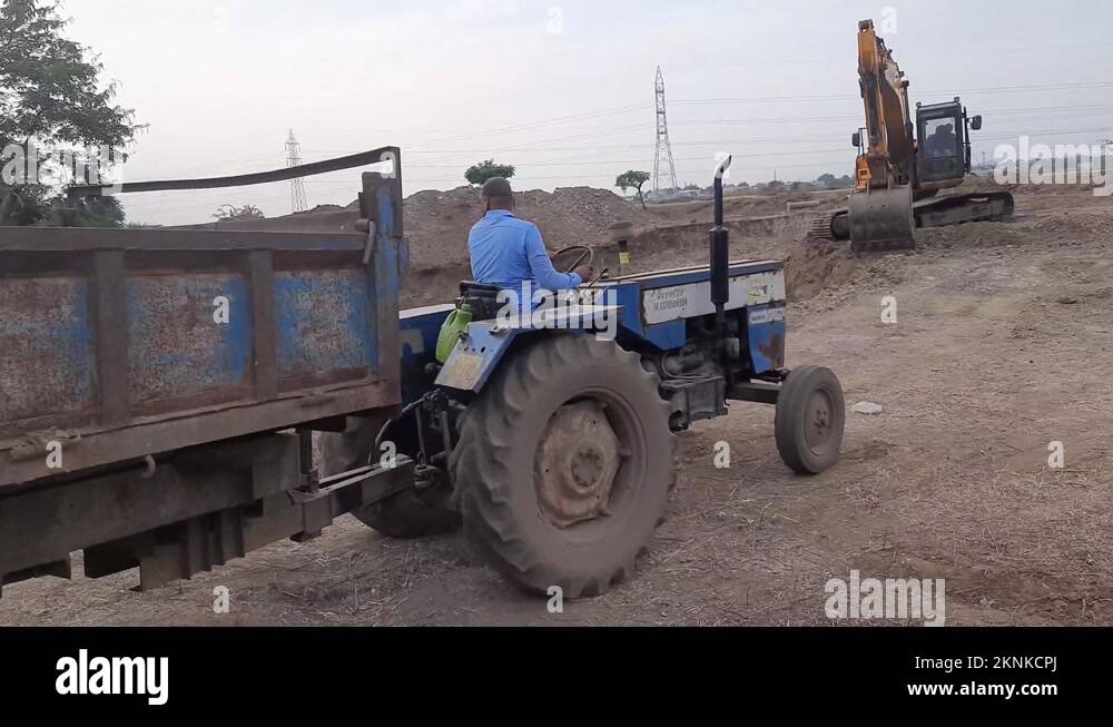 A tractor driver drives a tractor to load and unload soil Moorum by ...