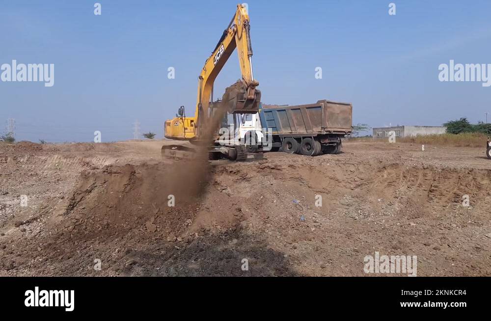 An excavator loads sand Moorum into a dumper truck at the construction ...