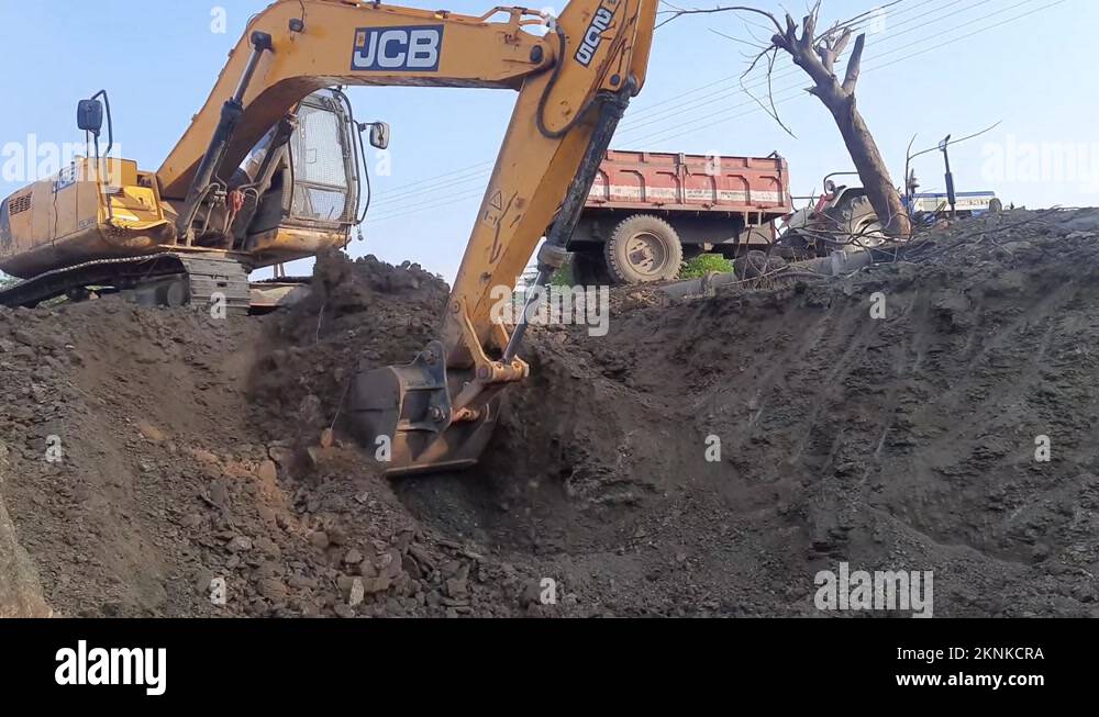 A JCB excavator machine loads Moorum soil into a tractor at ...