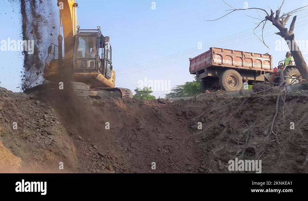 A poclain machine excavator machine loads Moorum soil into a tractor at ...