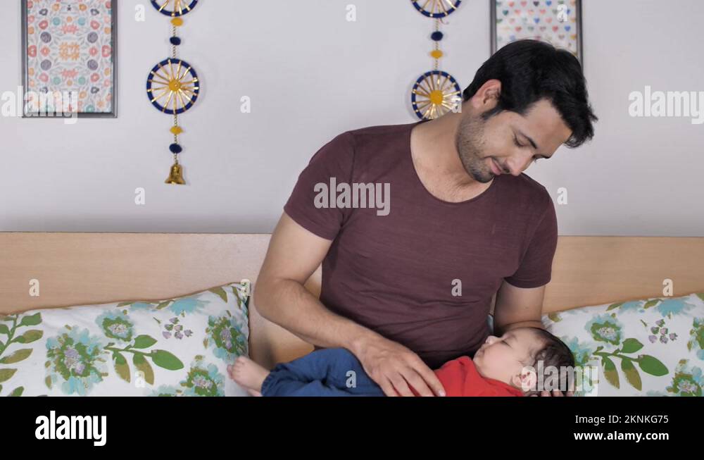 A loving Indian caring father patting his little daughter to sleep on ...