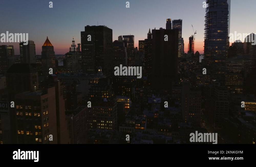 Fly above city at dusk. High rise buildings with lighted windows ...