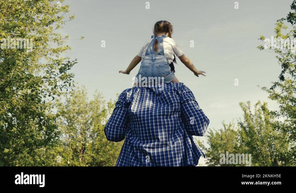 Dad walks with his daughter on his shoulders, the kid waves his arms ...