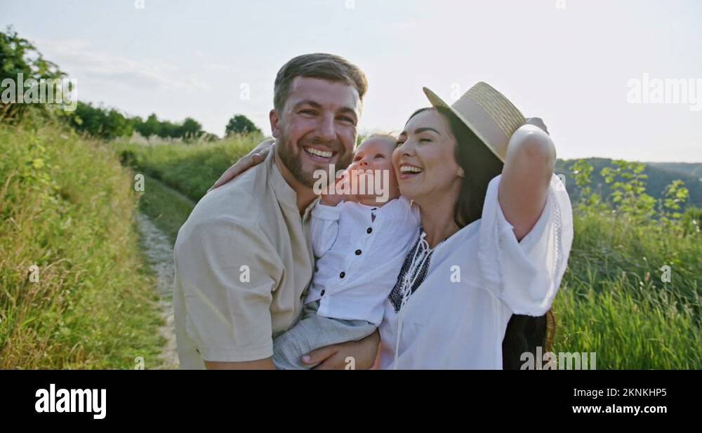 Joyful young parents hugging their infant child as they pose close ...