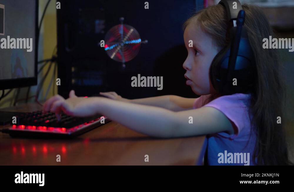 A child with headphones plays an online video game on the computer. The ...