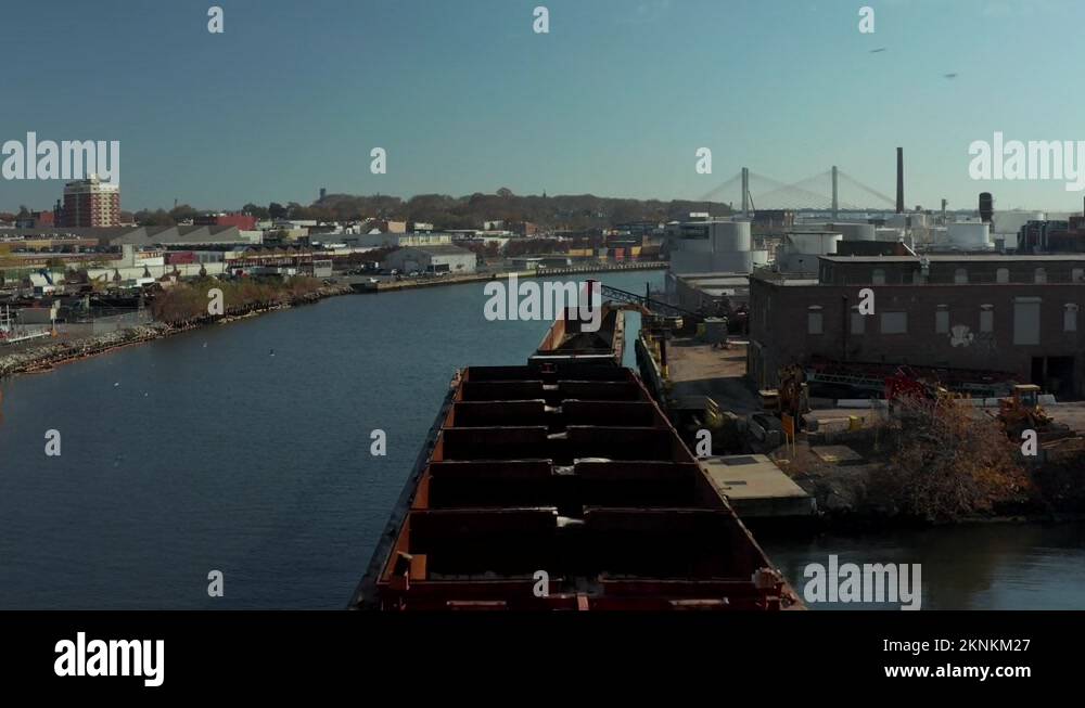 Fly over cargo ship moored at bank. Loading loose material on barge ...
