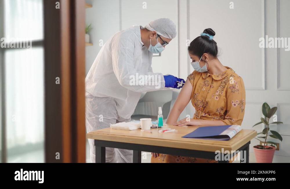 Doctor injecting a vaccination in arm of a young Indian Asian female ...