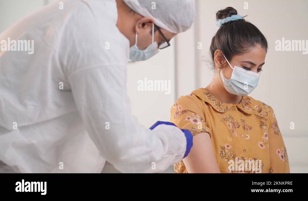Doctor injecting a vaccination in arm of a young Indian Asian female ...
