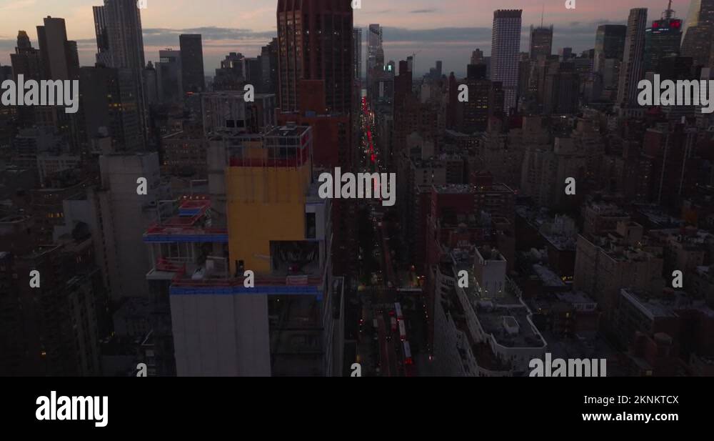 Fly between high rise buildings in city at twilight. Long straight ...