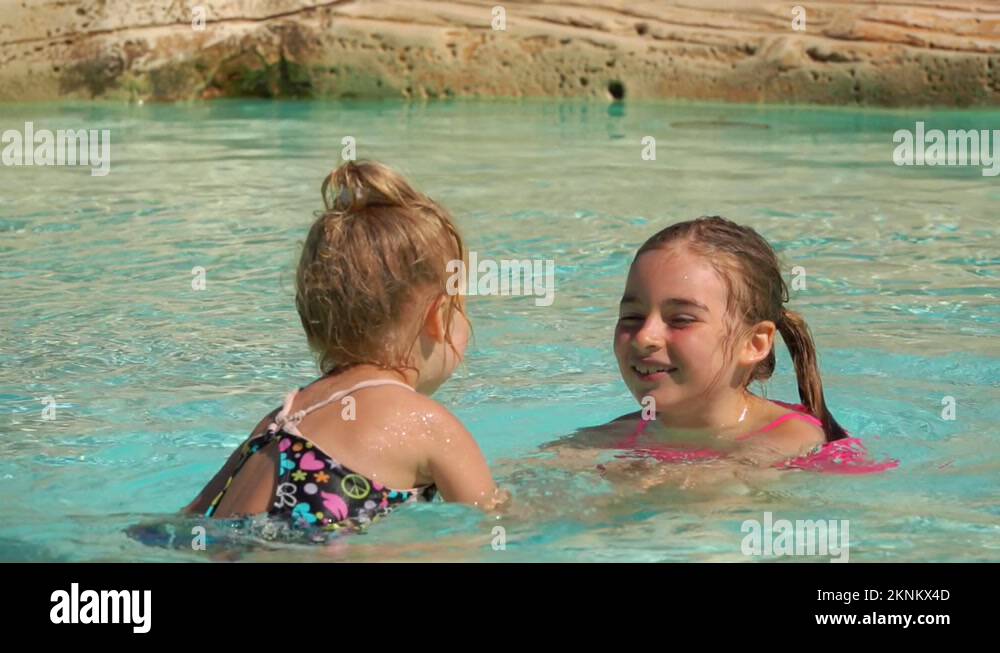 Two sibling girls are playing together in the swimming pool Stock Video ...