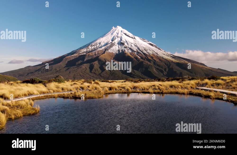 Tourists waiting for reflection of Taranaki volcano at Pouakai Tarn ...