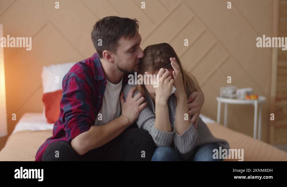Man calms crying woman sitting on bed in bedroom, hugs and kisses her, front Stock Video Footage ...
