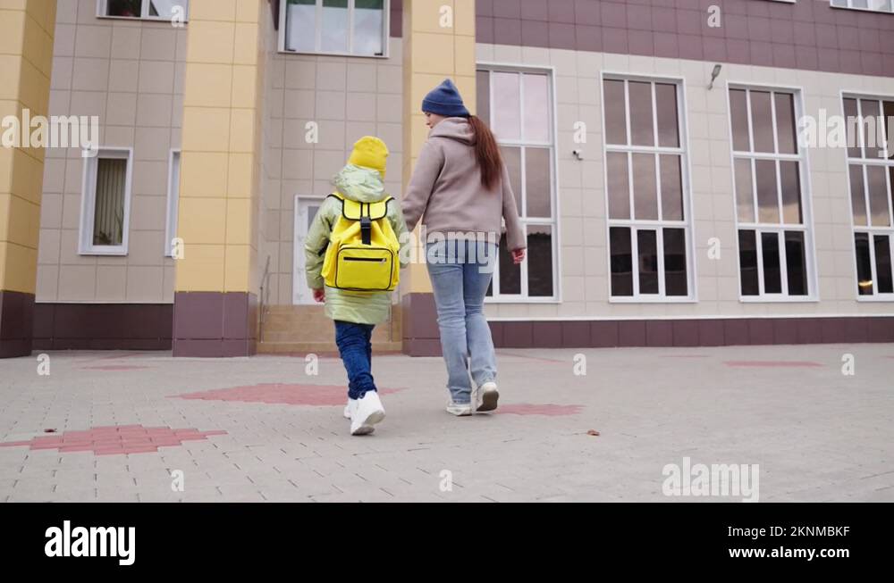 mother leads the little kid to school in the first grade, mom holds the ...