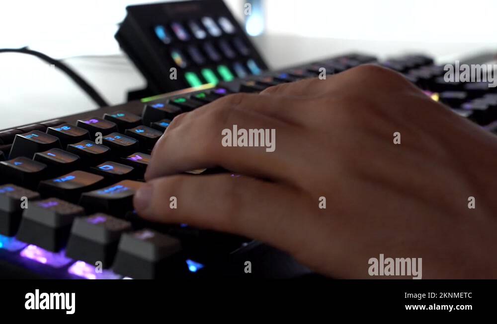 Hand of a gamer typing and using a colourful keyboard, close up of an ...