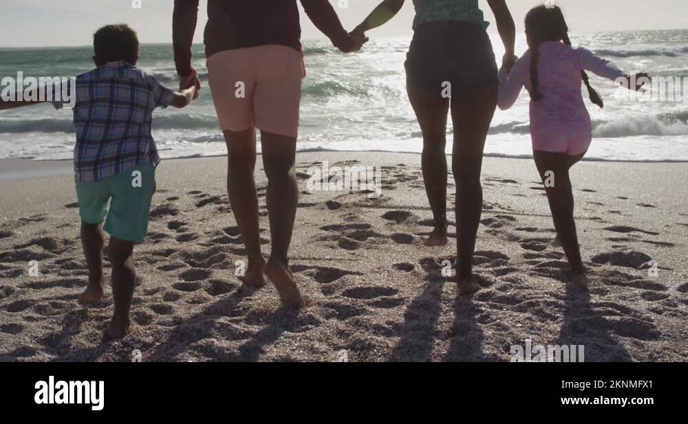 Back view of hispanic mother, father, son and daughter holding hands ...
