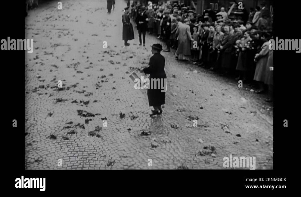 1940s: Woman spreads flowers on road. Hitler waves to crowds from ...