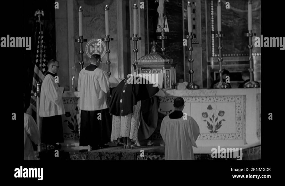 1960s: Priests kneel and pray at altar in cathedral. Cardinal blesses ...