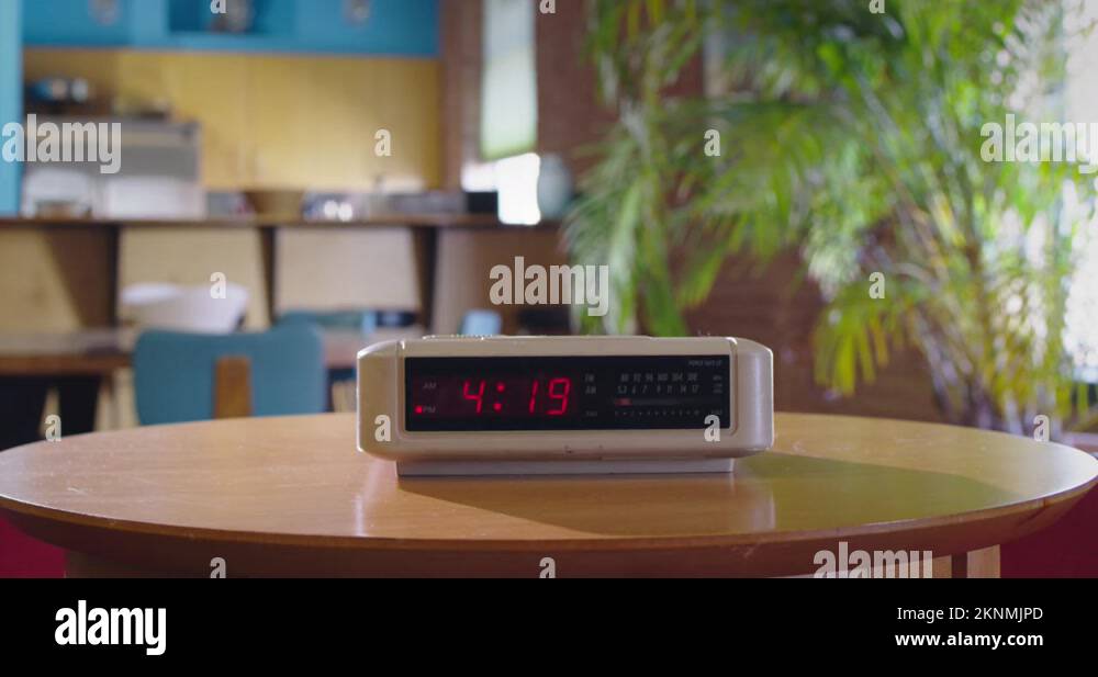 Detail of vintage digital alarm clock sitting on side table as time ...