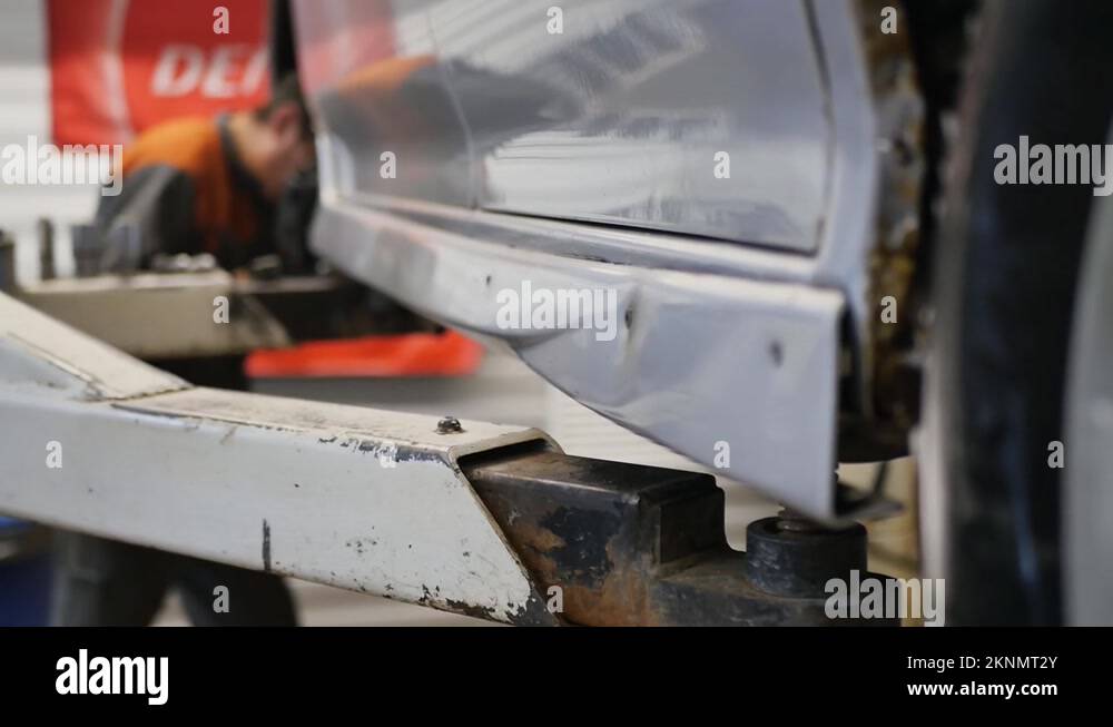 a mechanic in a car repair shop repairs a car raised on a car lift ...
