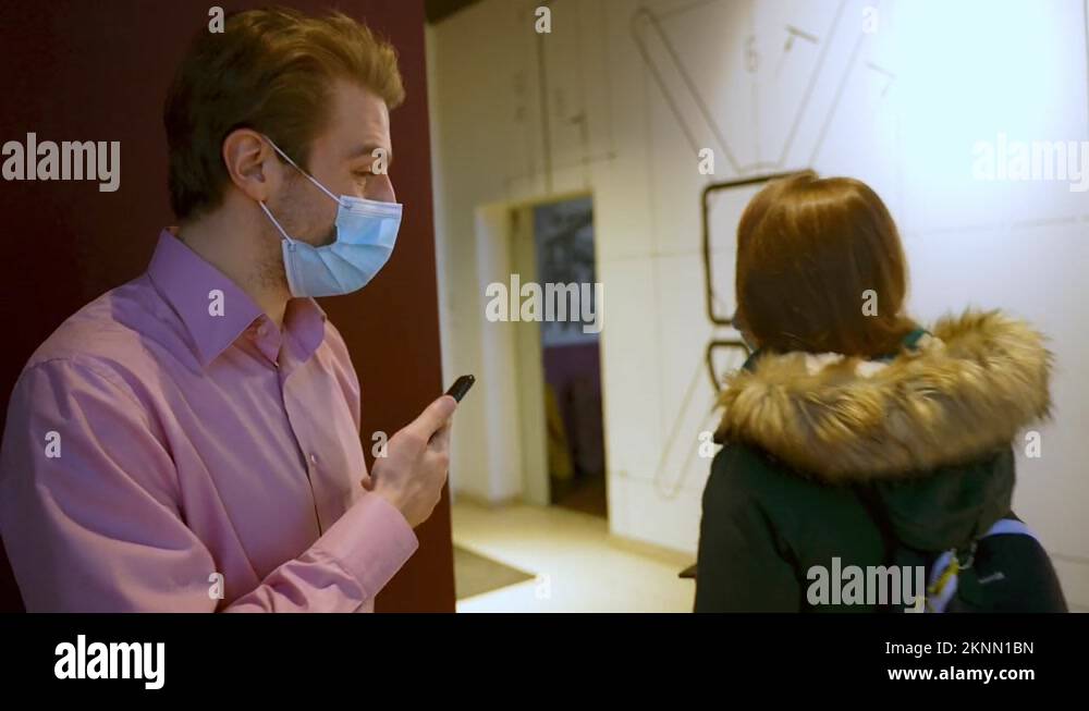 Employee scans QR codes at the entrance to the building from visitors ...