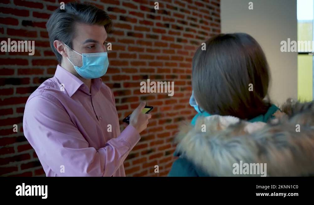 Employee scans QR codes at the entrance to the building from visitors ...