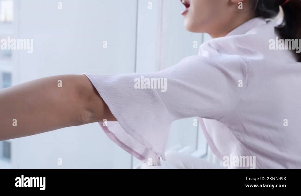 woman open curtain to reveal the city luxury high rise buildings during ...