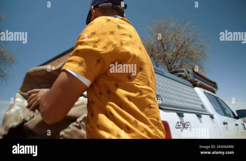 Handheld tracking shot of a tourist folding and putting a rooftop tent ...