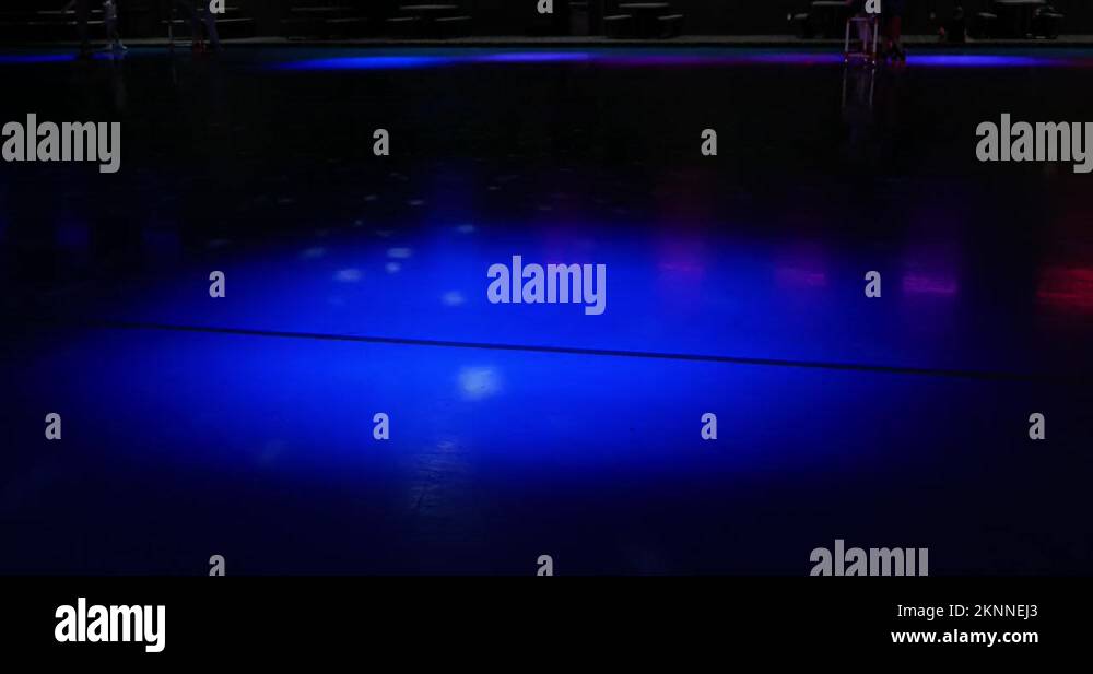 Blue and red lights flashing on roller skating rink with people skating ...