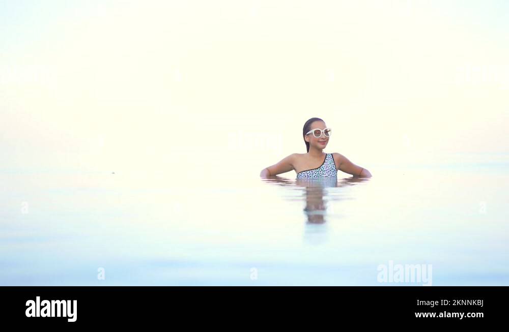 A woman leans along the edge of a swimming pool appears to be floating ...
