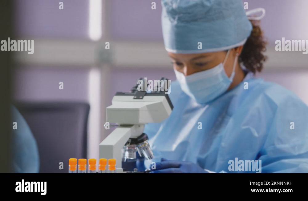 Female Lab Worker Wearing PPE Analysing Slide Under Microscope Stock ...