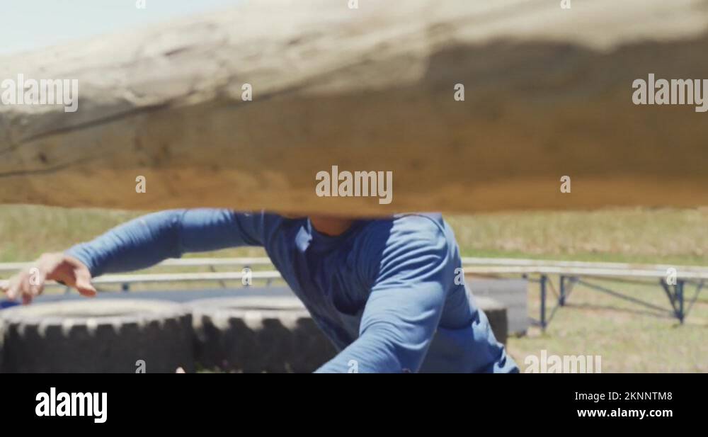 Fit african american man climbing under and over hurdles in the sun on ...