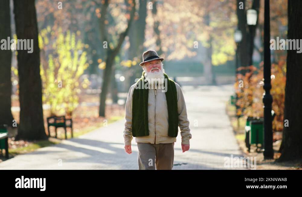 In front of the camera walking happy old man have a walk in the middle ...