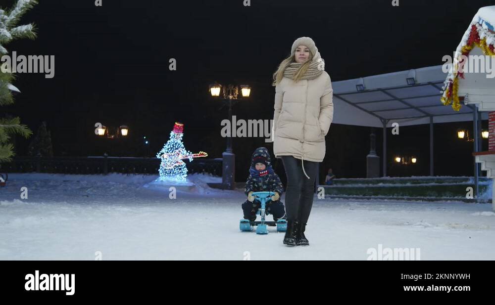 Young cute mom is driving her little son on a sled, front view Stock ...