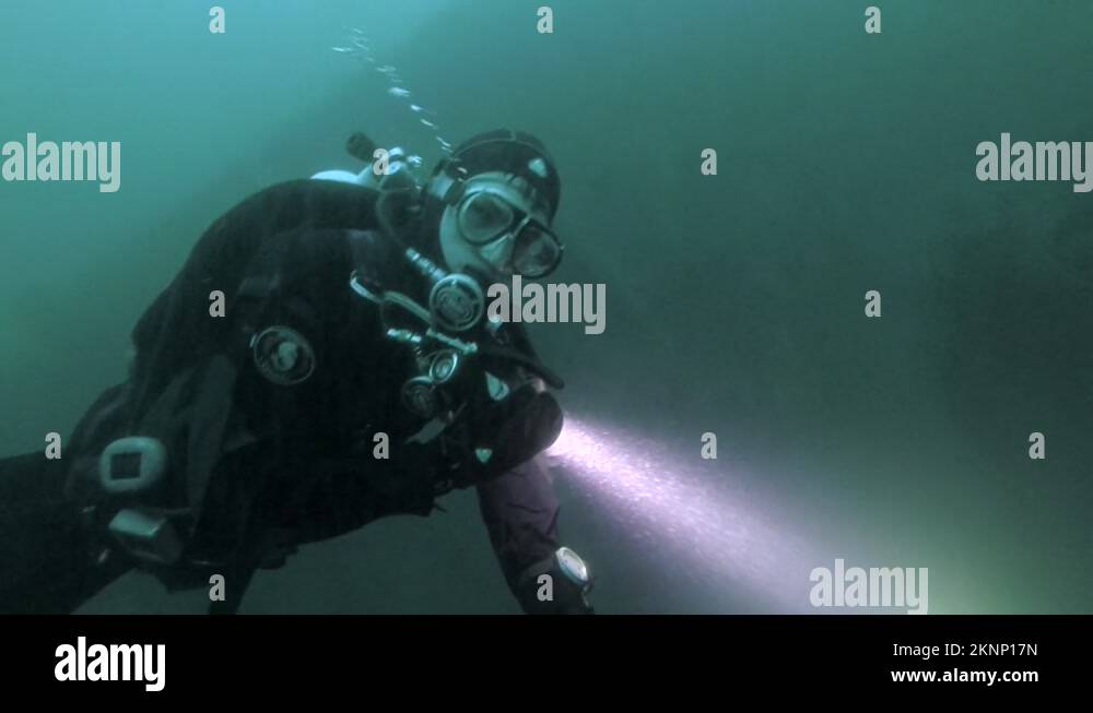 Deep sea scuba diver explores submerged ship wreck with flashlight ...