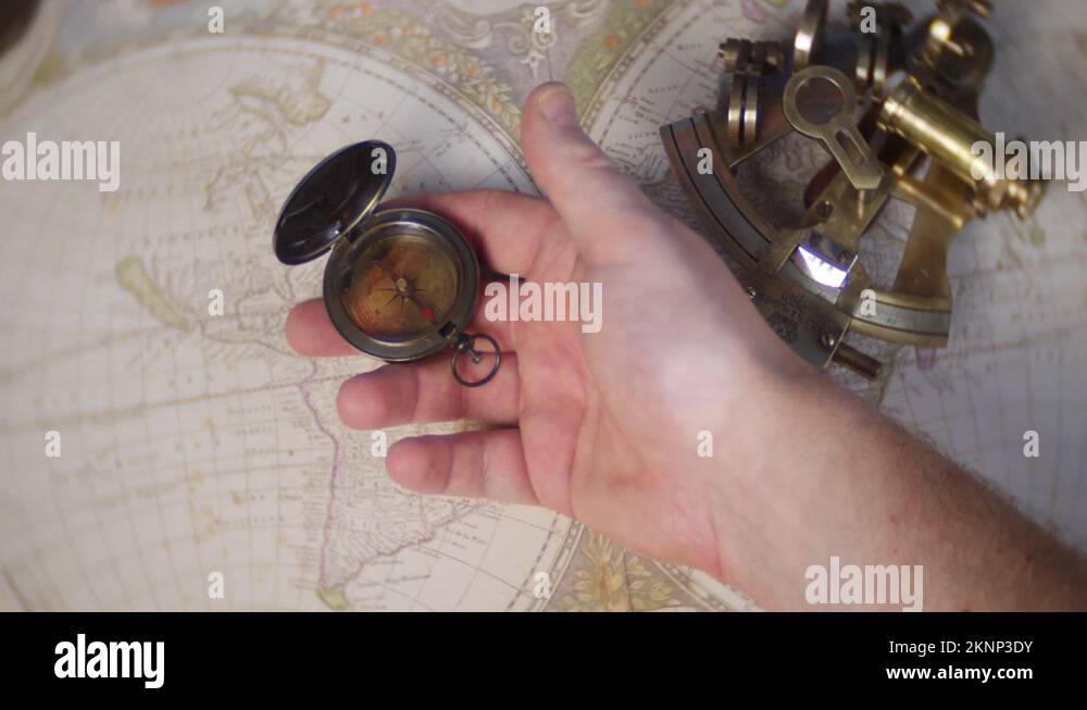 A man uses an antique compass to plot a course on a vintage world map ...