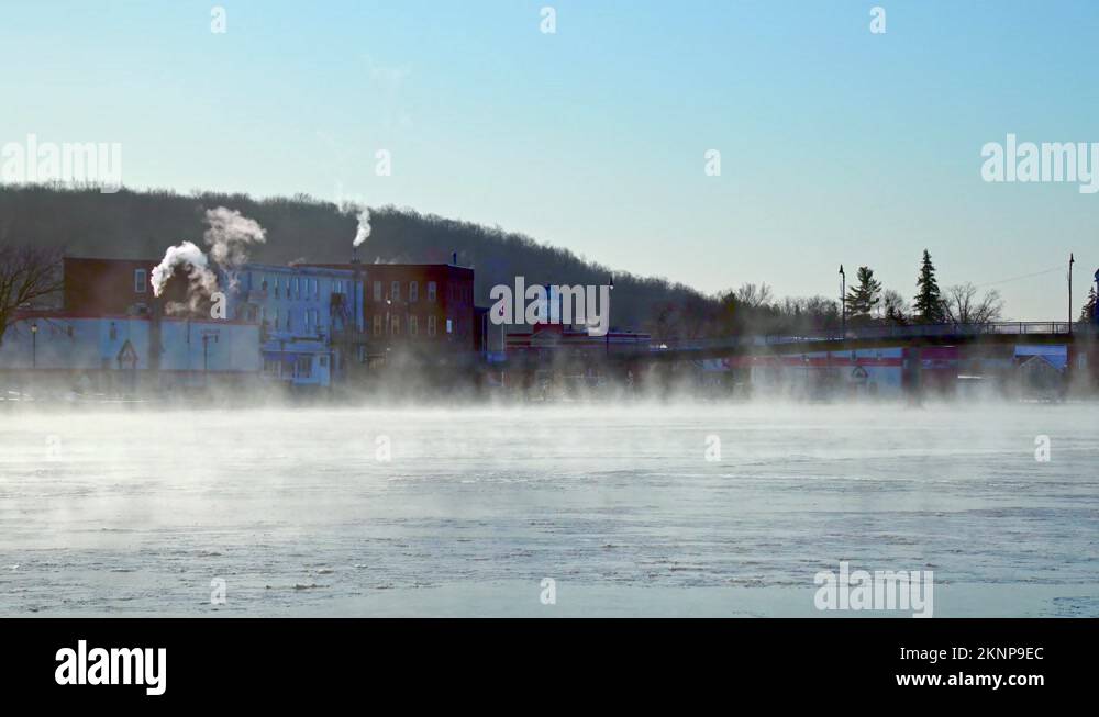 Mist rising from a freezing river as cars cross over a small town's ...
