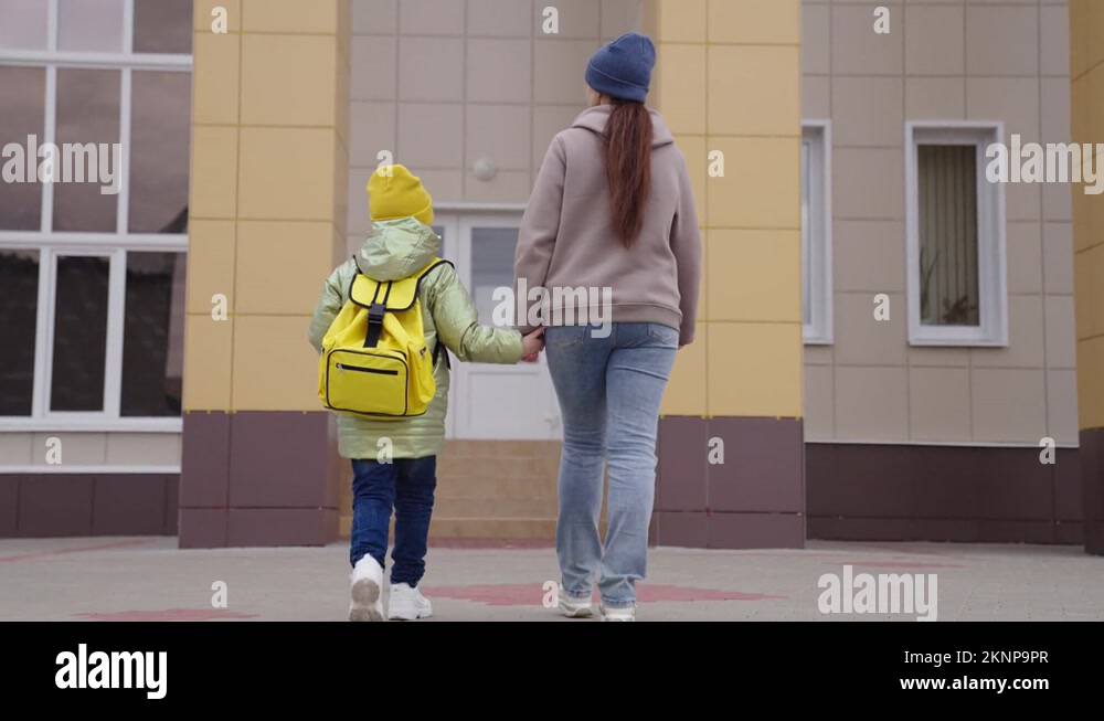 affectionate mother leads the child back to school, to teach first ...