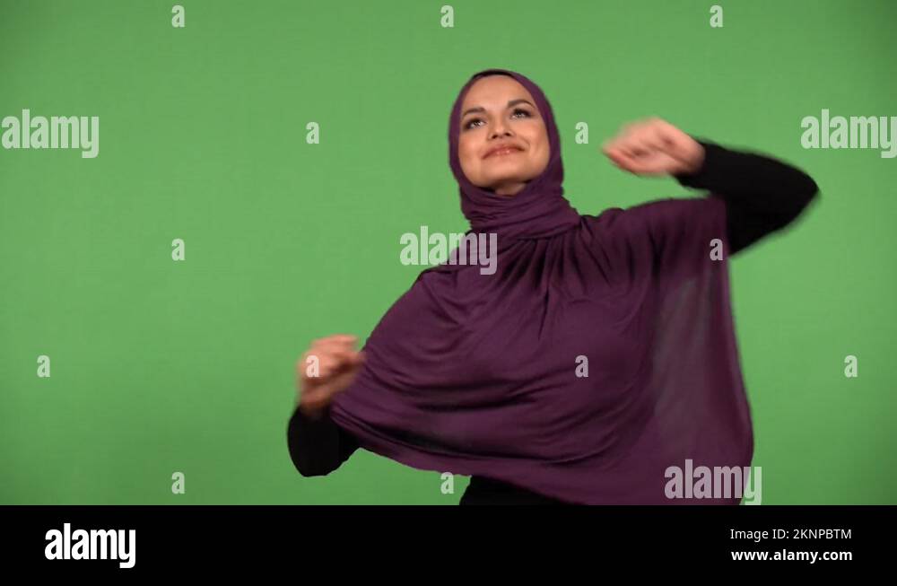 A young beautiful Muslim woman dances with a smile - green screen ...