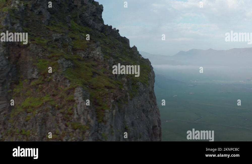 Rocky outcrop of tall cliff. Sliding reveal on wide valley with houses ...