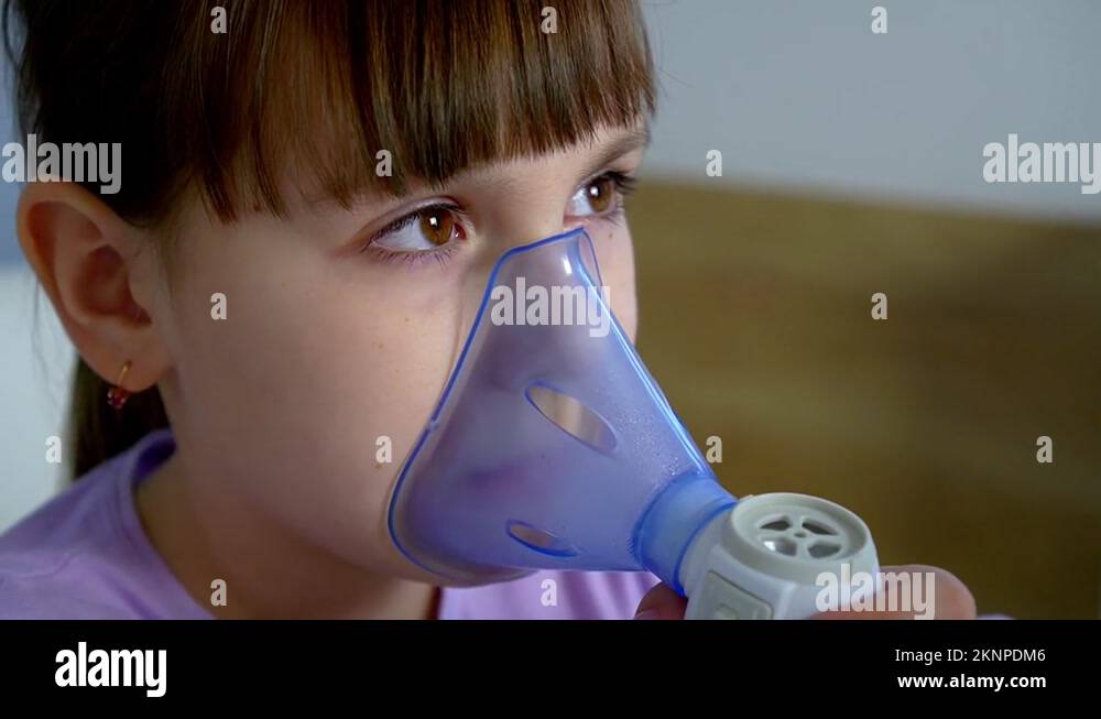 Little girl makes inhalation with medical nebulizer holding mask on ...