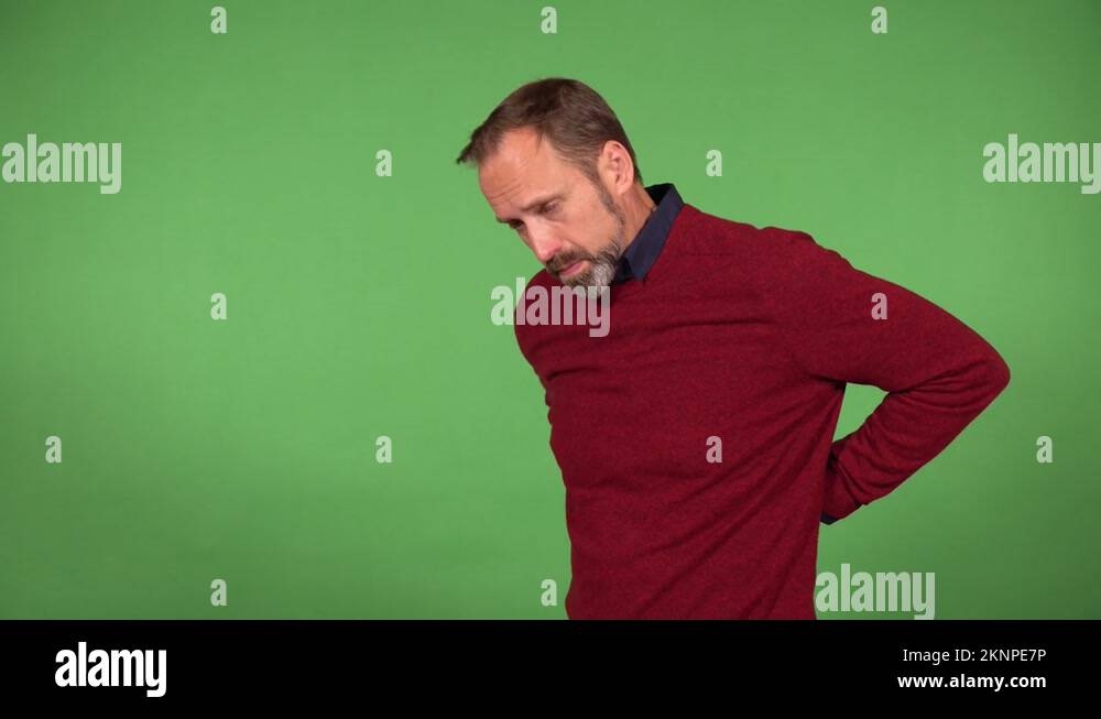A middle-aged handsome Caucasian man has back pain - green screen ...
